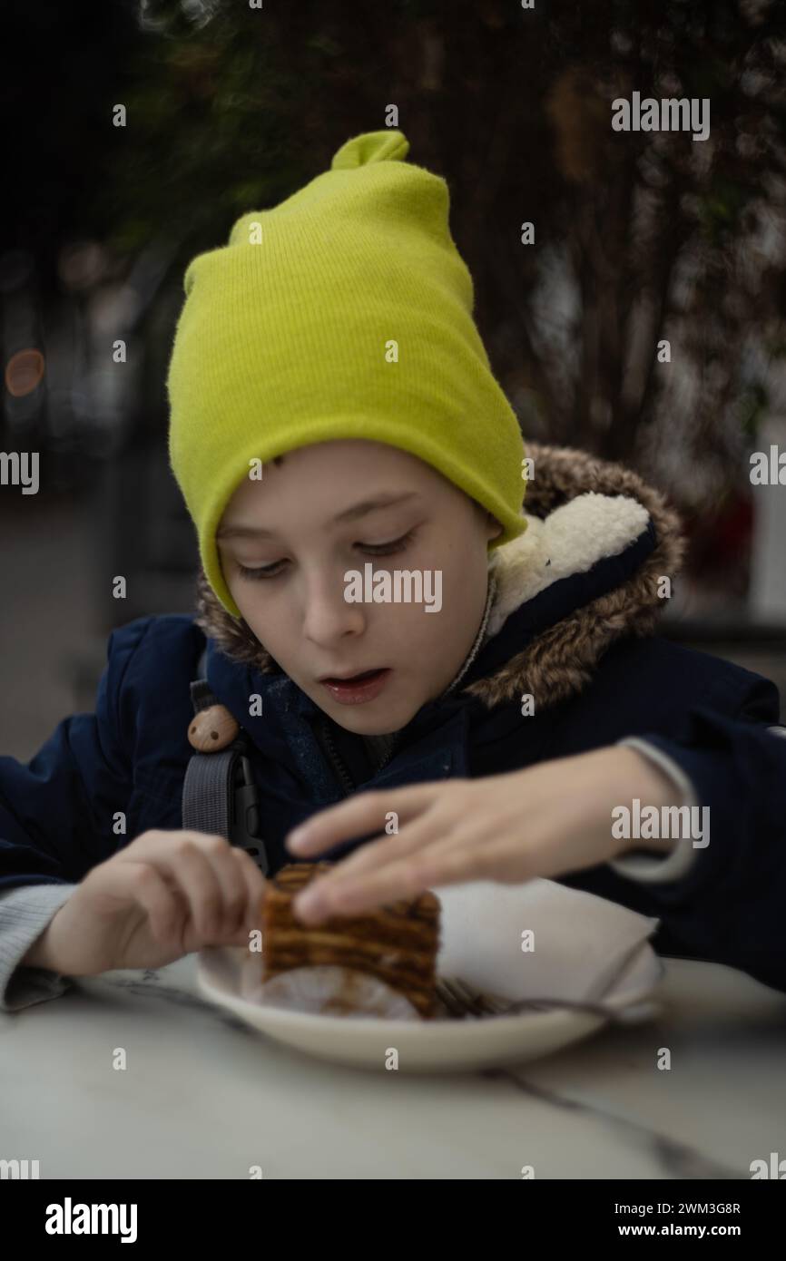 Nice boy eating cake in outdoor cafe Stock Photo - Alamy