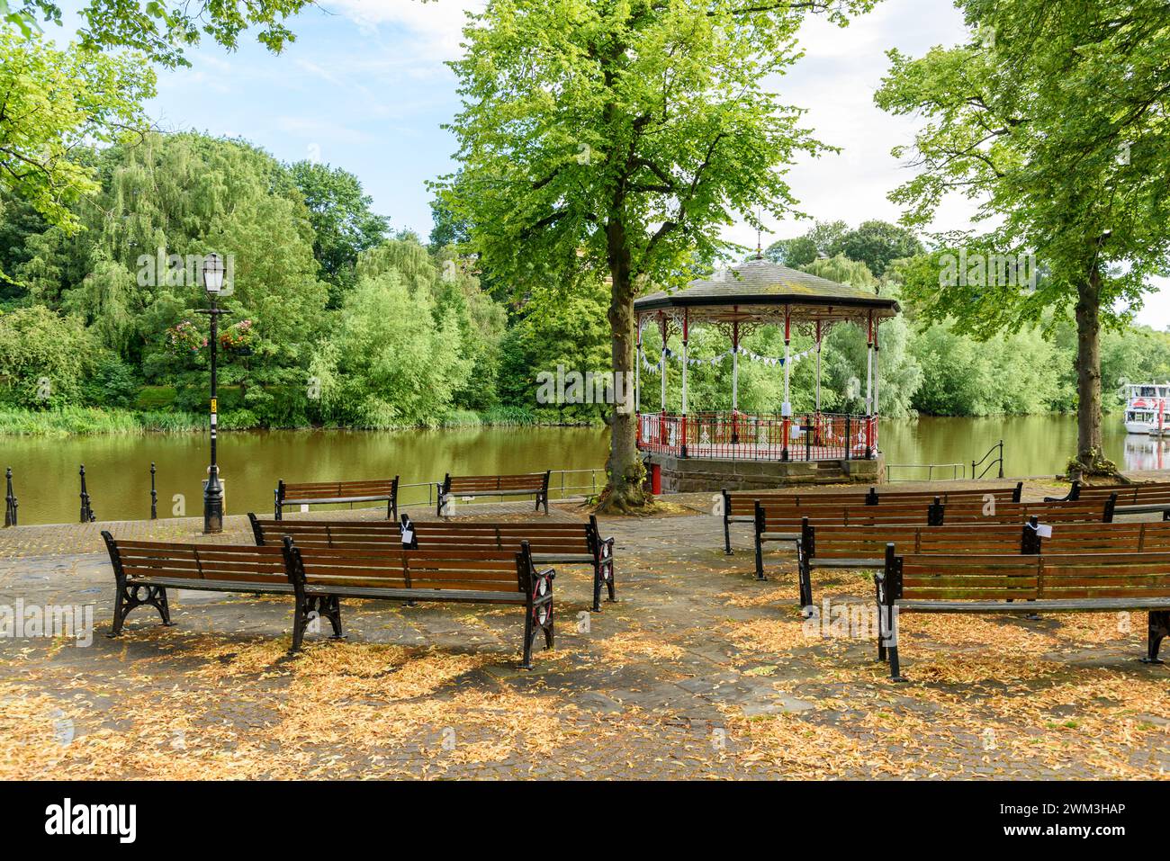 Bandstand and woodedn benches in a park on the bank of a river on a ...