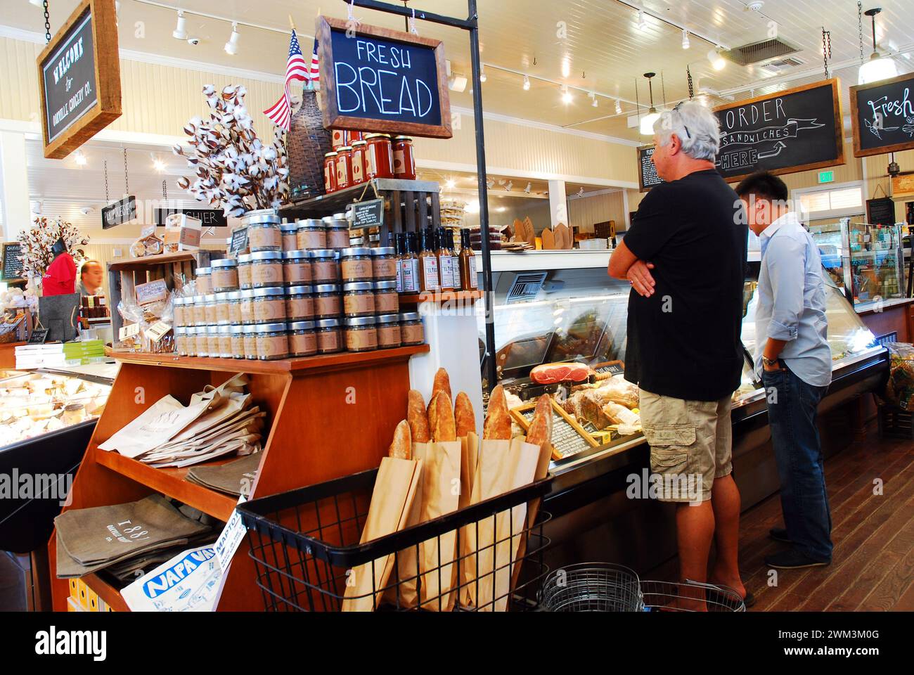 An adult couple order fresh, grass fed meat at an organic grocery store ...
