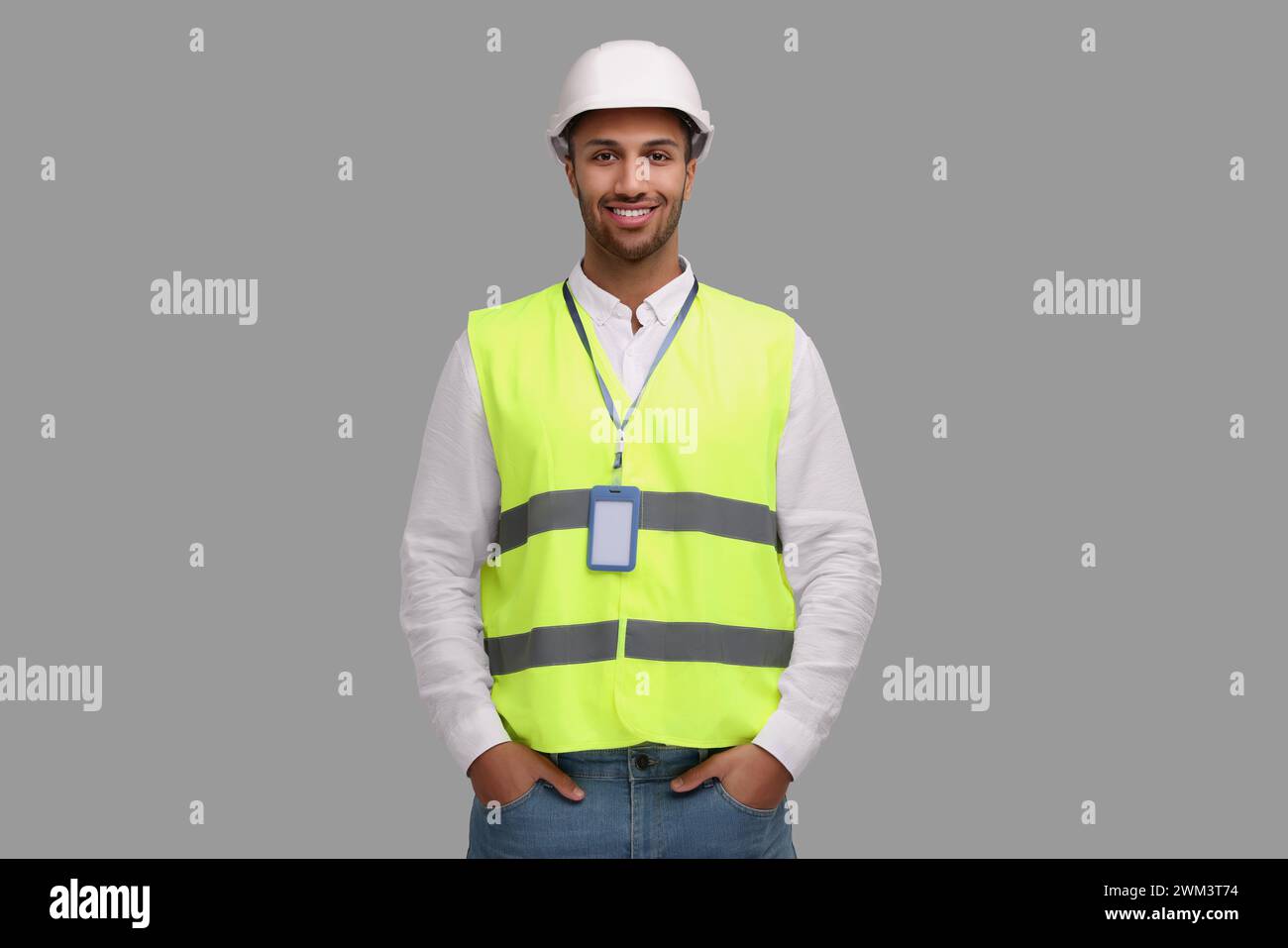 Engineer with hard hat and badge on grey background Stock Photo - Alamy
