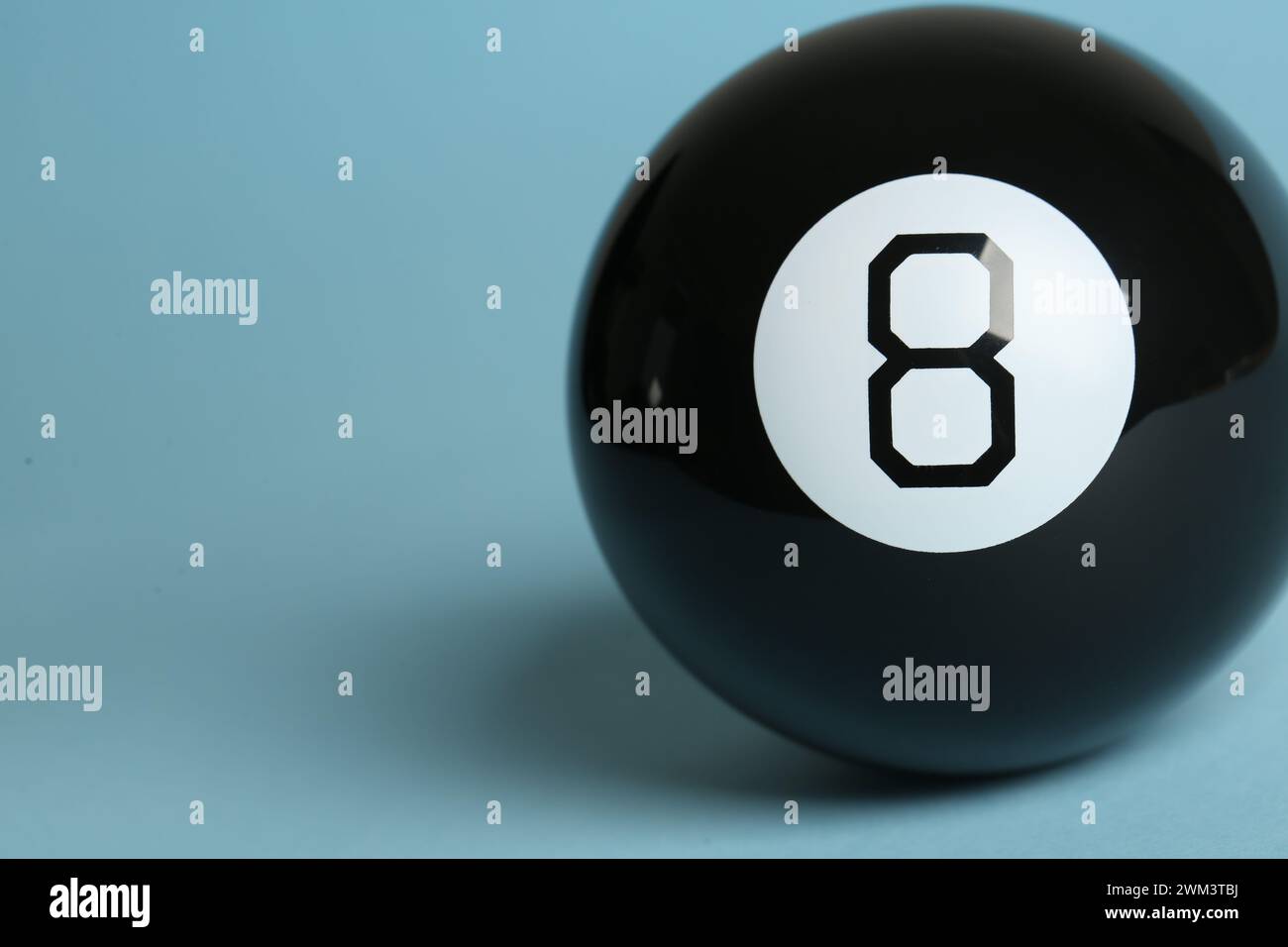 One magic eight ball on light blue background, closeup. Space for text ...