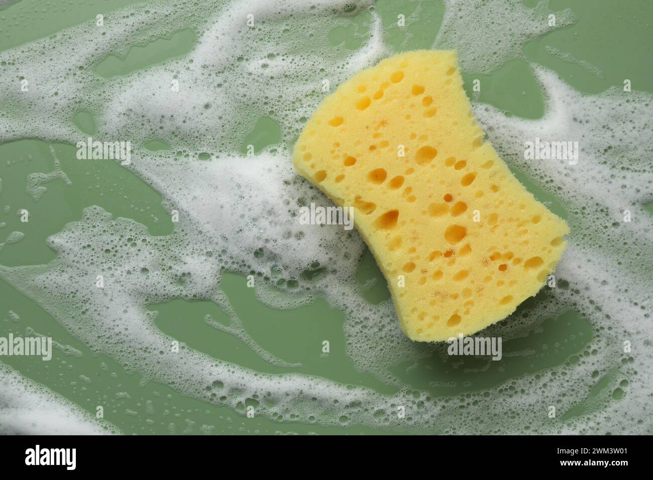 Yellow sponge with foam on green background, top view Stock Photo - Alamy