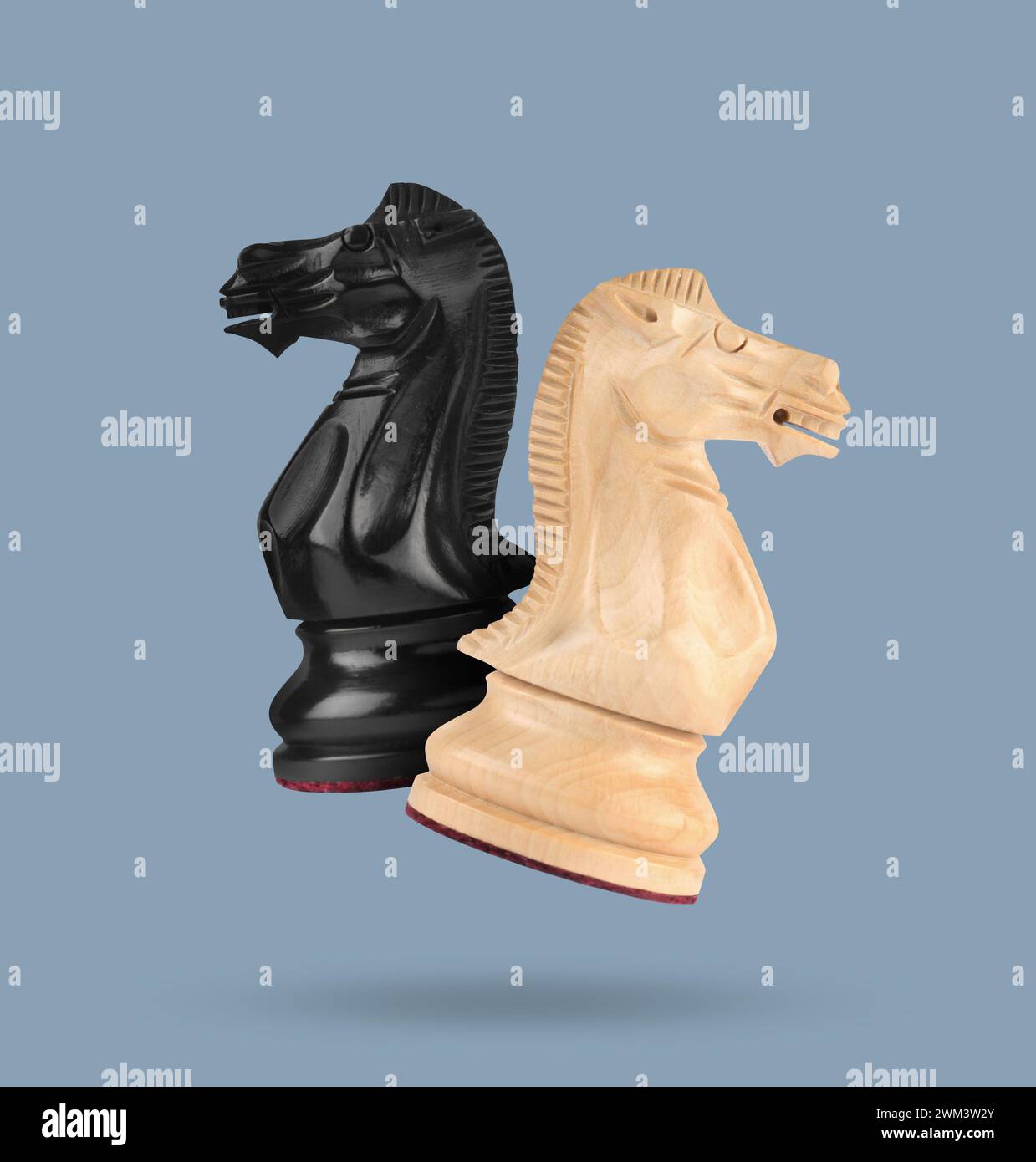 Wooden chess knights in air on greyish blue background Stock Photo - Alamy