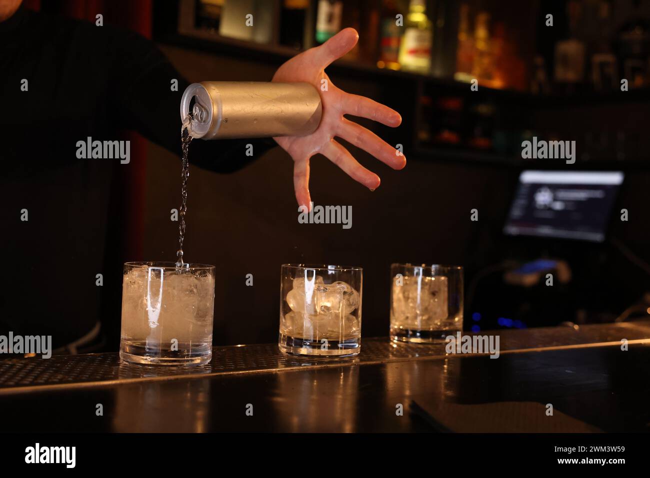 Bartender pouring energy drink into glass at counter in bar, closeup ...