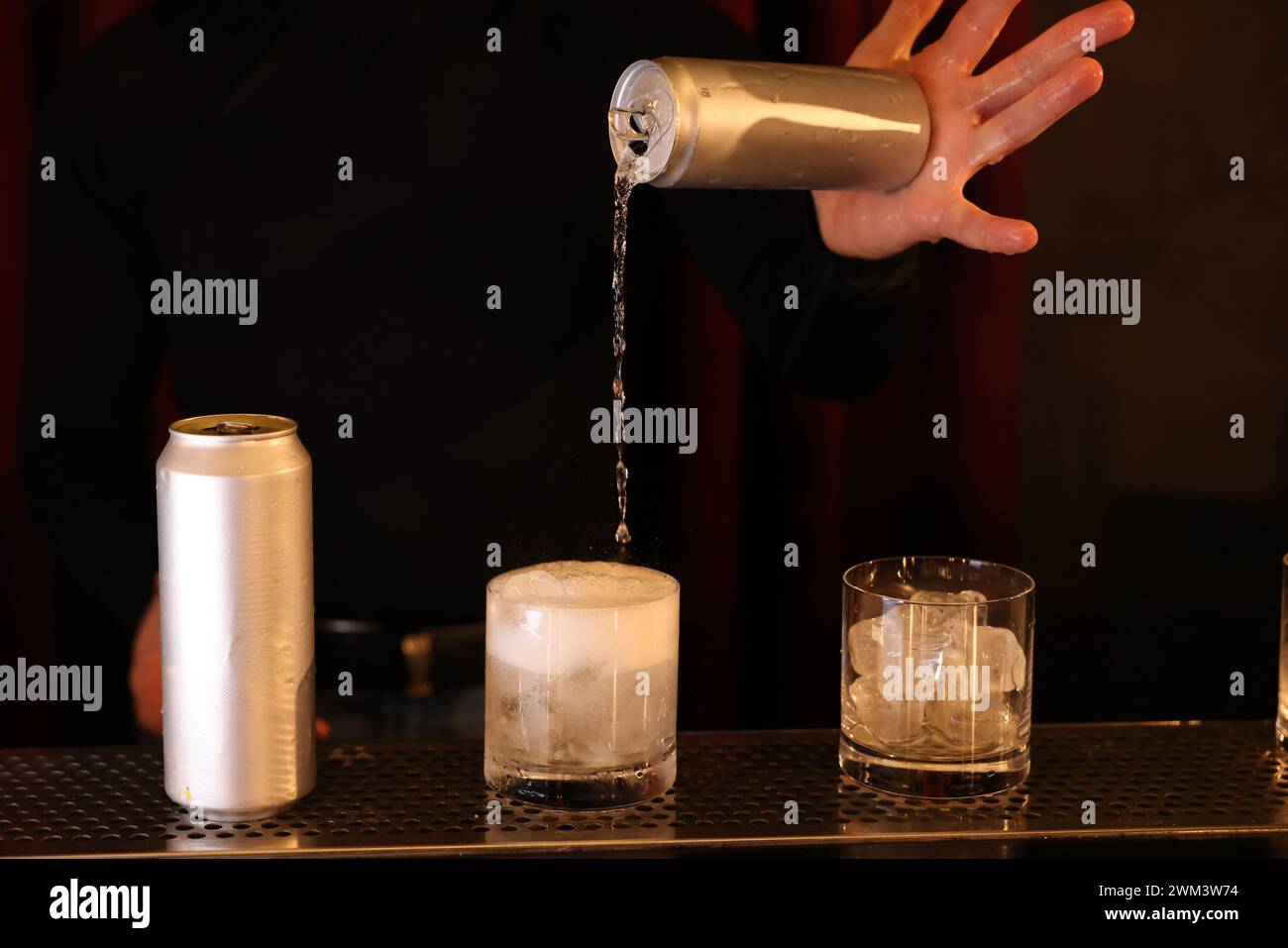 Bartender pouring energy drink into glass at counter in bar, closeup ...