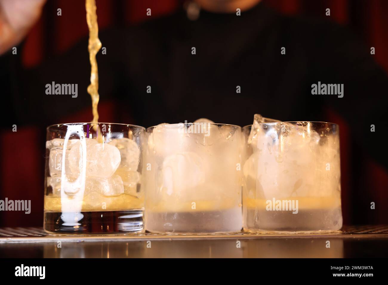 Bartender pouring energy drink into glass at counter in bar, selective ...