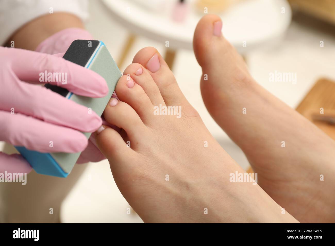 Professional pedicurist filing client`s toenails in beauty salon ...