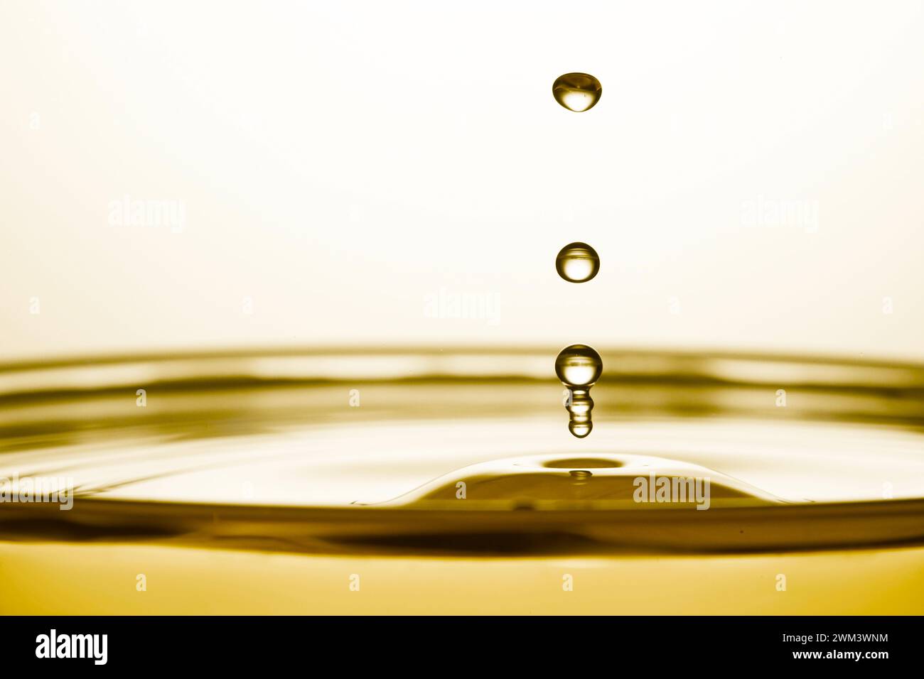 Splash of golden oily liquid with drops on white background, closeup ...