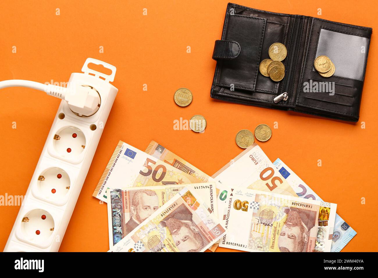 Wallet with money, power socket and plug on orange background ...