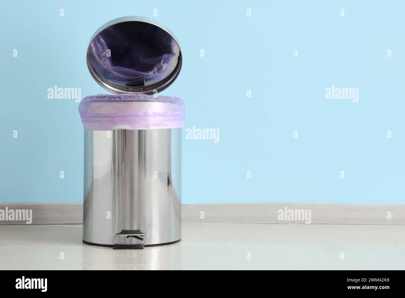 Modern trash bin with foot pedal and open lid near blue wall Stock ...