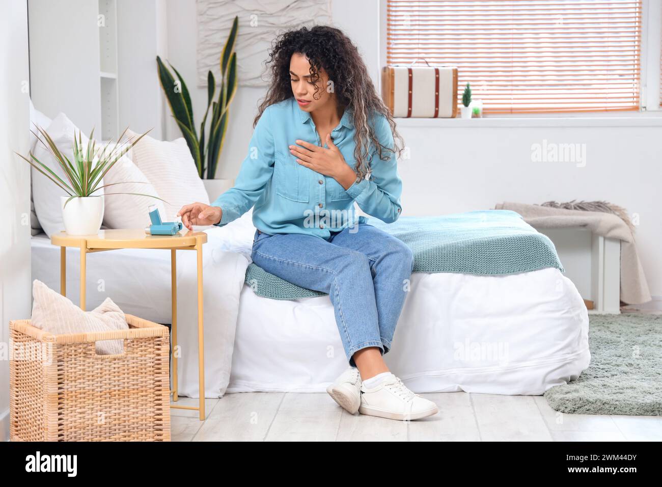 Young African-American woman taking asthma inhaler from table in ...