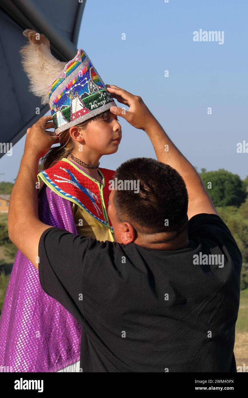 Native American father adjusting his daughter's decorative headpiece ...