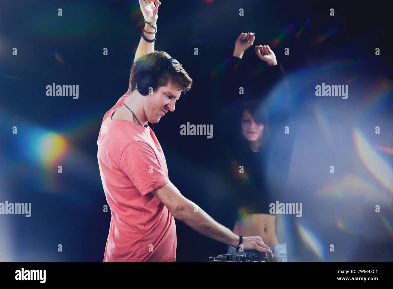 DJ raises hand in joy, woman in background dancing, both encapsulated ...