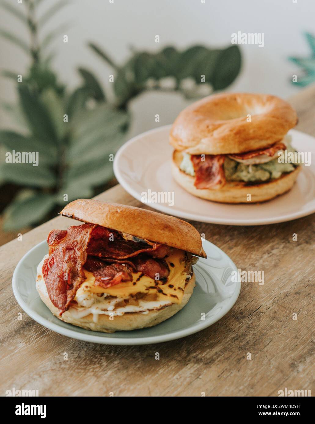 Two burgers filled with meat and eggs on a wooden table with white ...