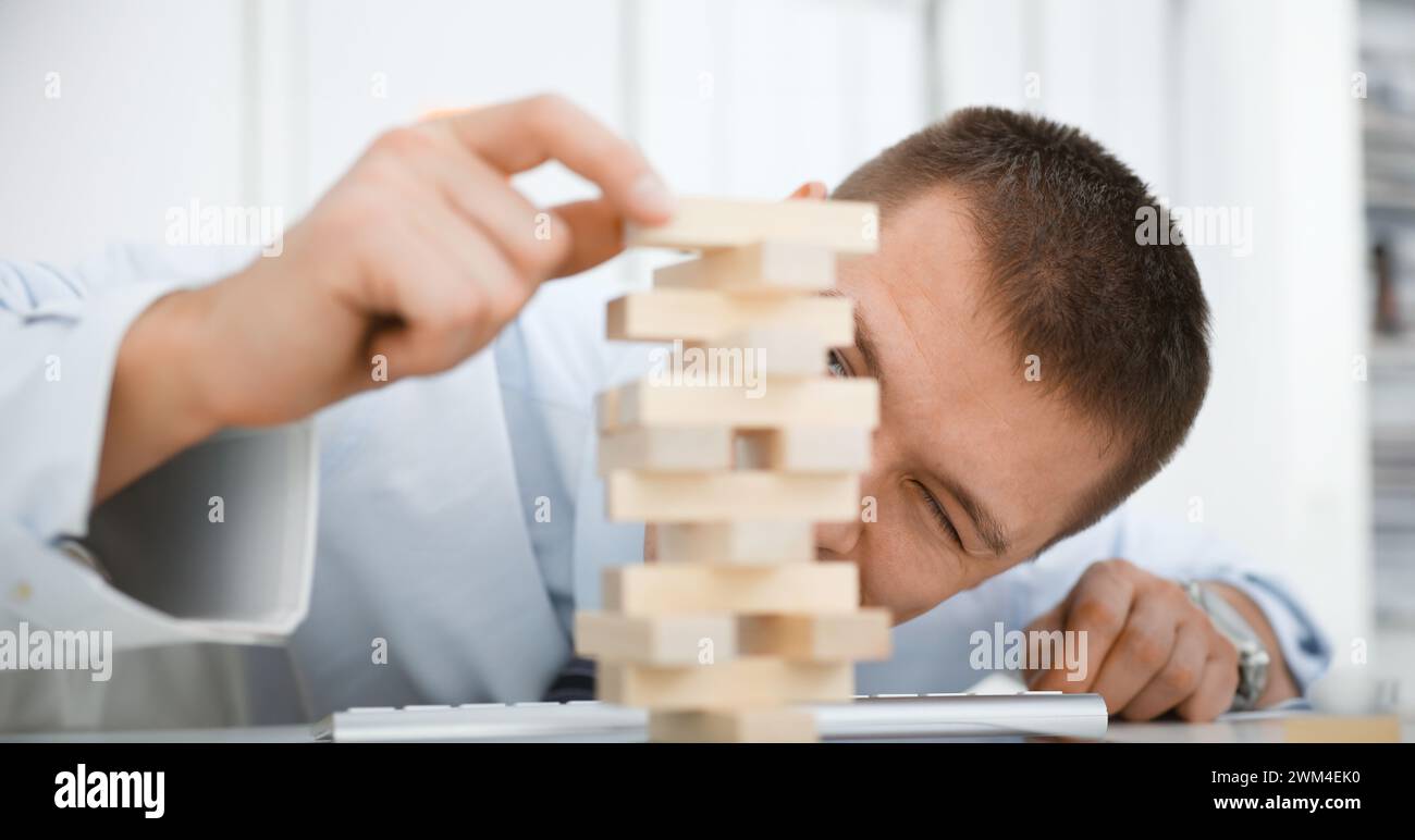 Businessman plays in a strategy of jenga hand Stock Photo - Alamy