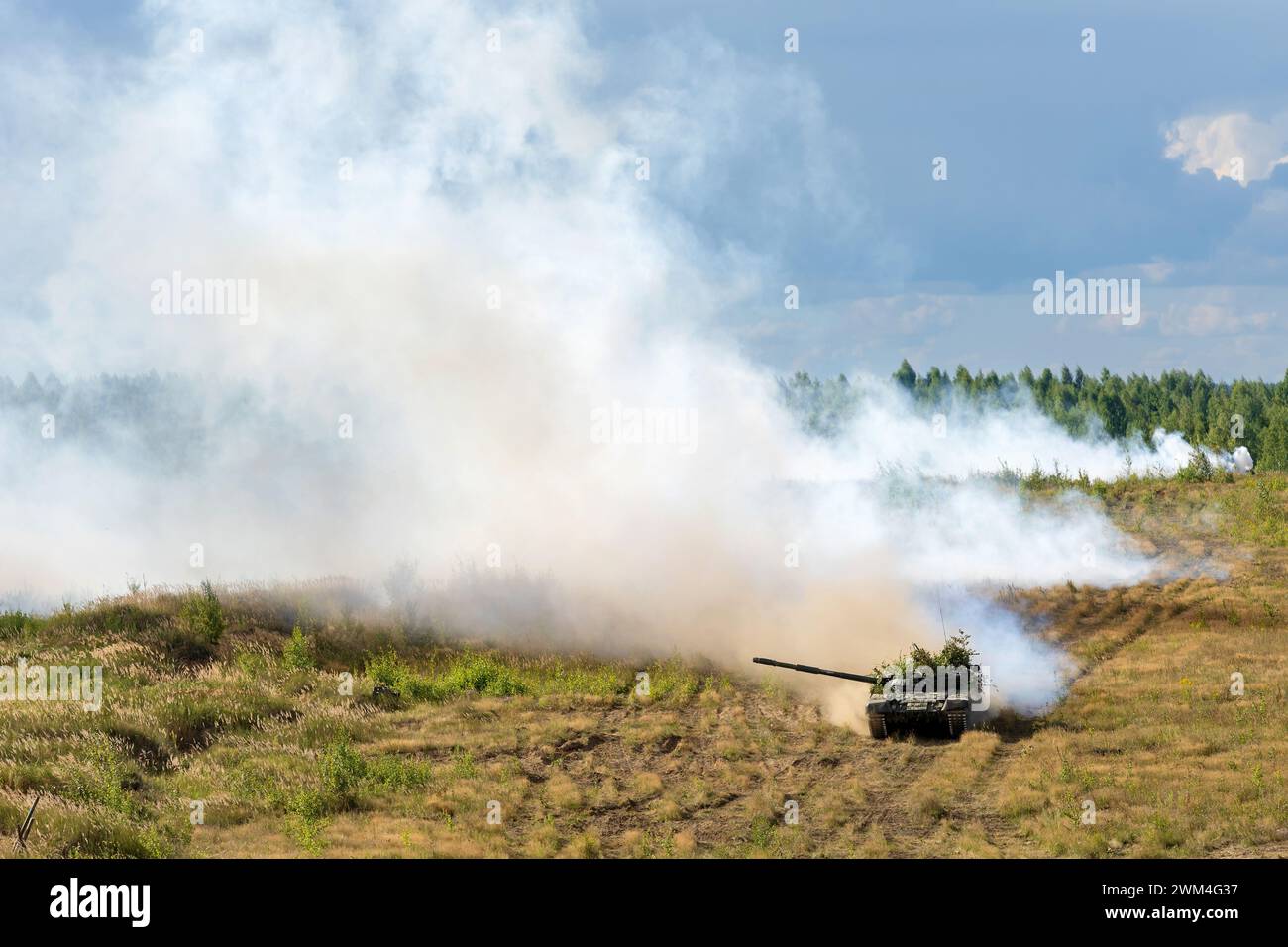 Heavy combat vehicles tanks drive around the butts and put up a smoke ...
