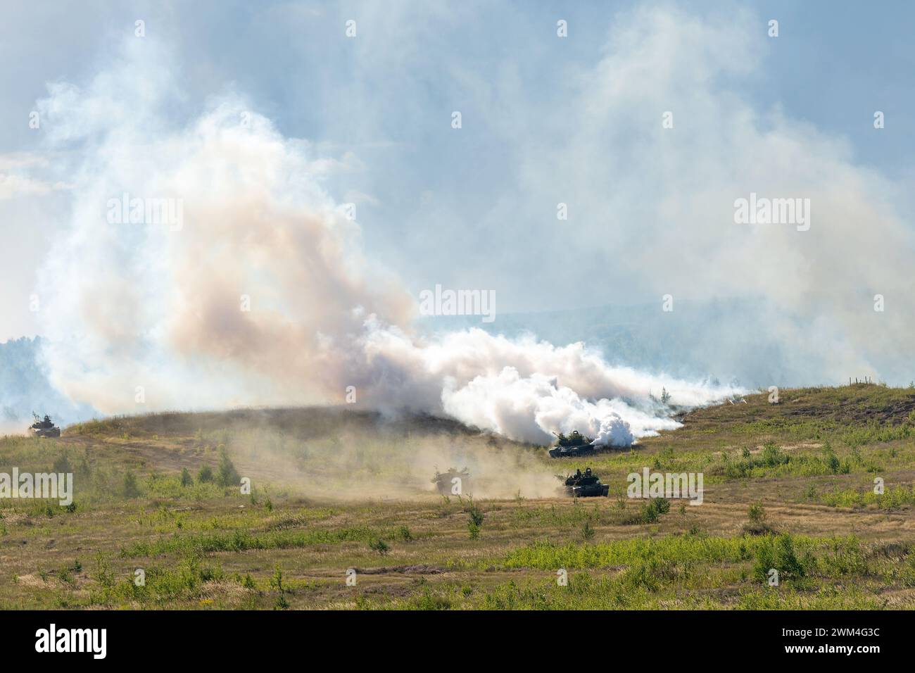 Heavy combat vehicles tanks drive around the butts and put up a smoke ...