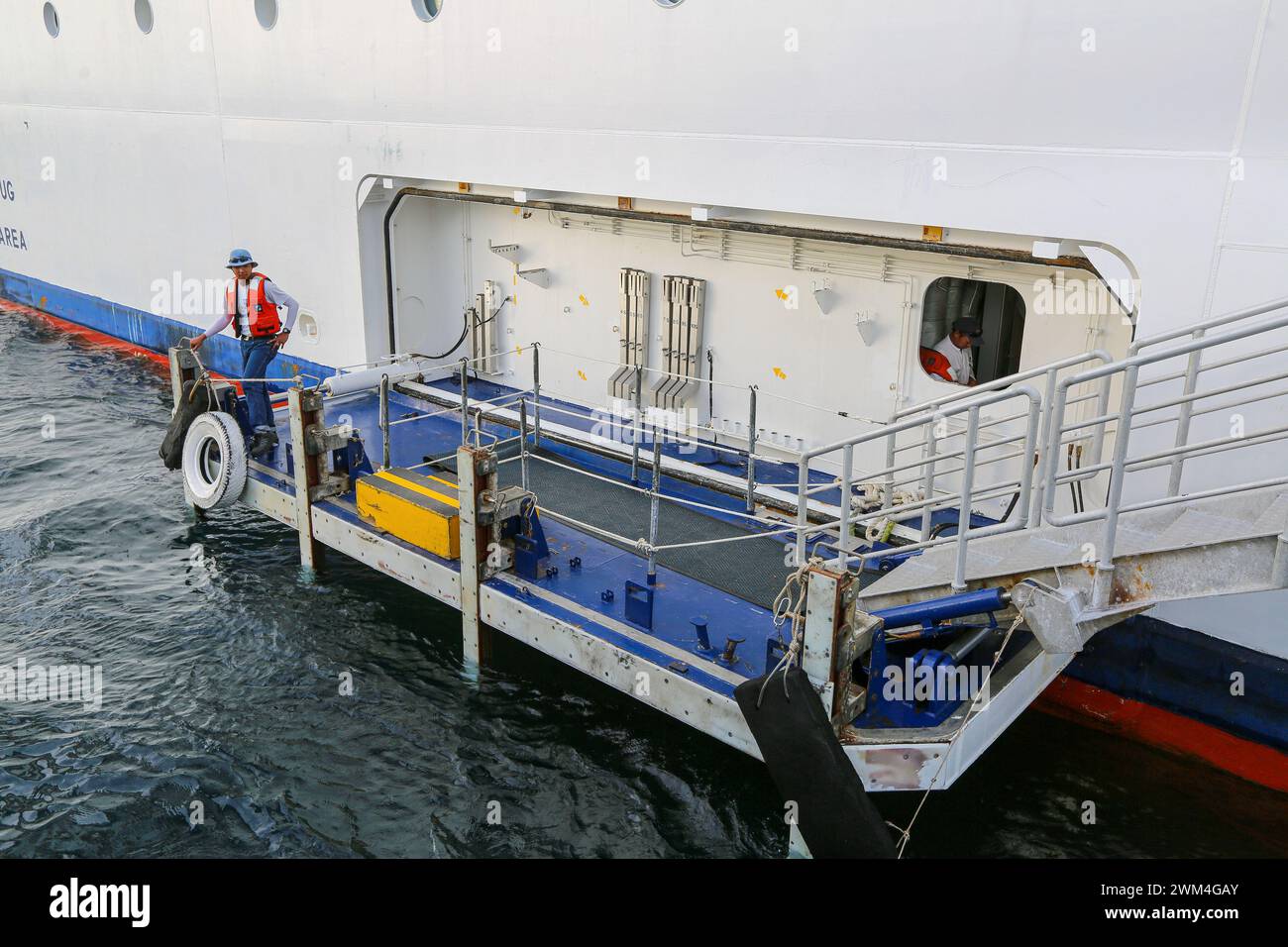 Crew member on boarding platform folding out from the cruise ship's ...