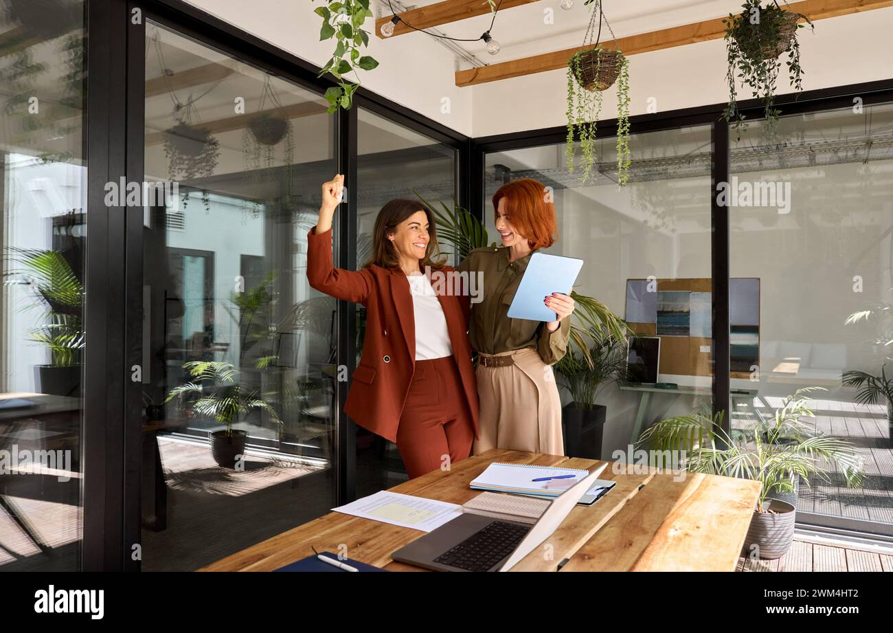 Two happy business women partners celebrating work success in office ...
