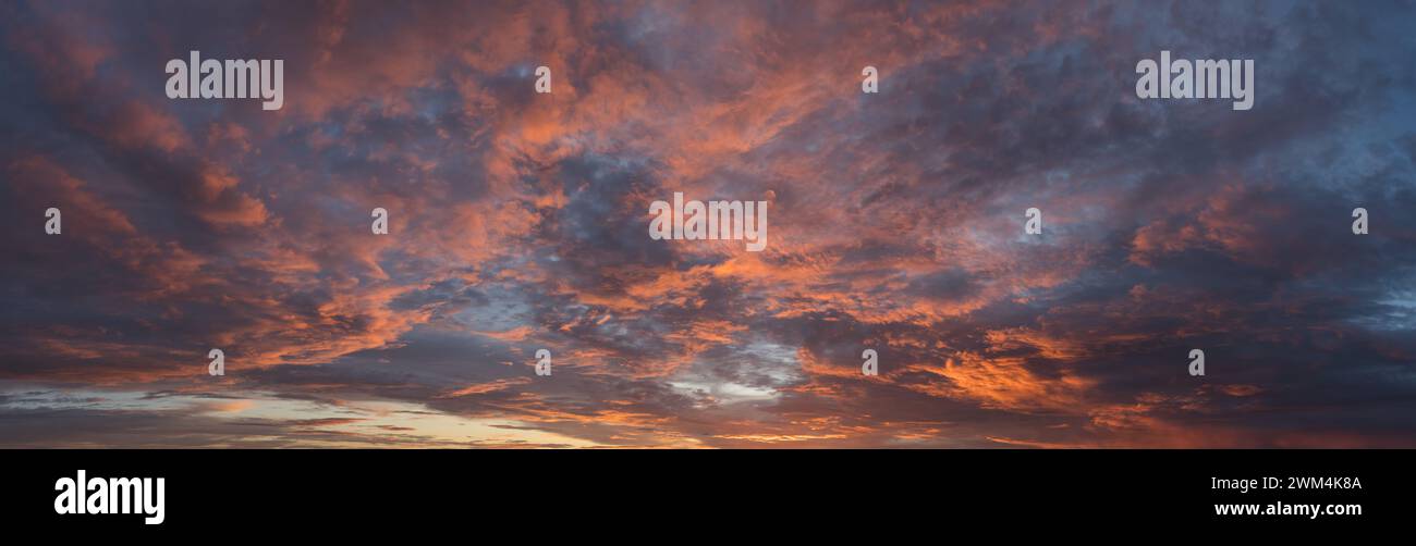 Ultrawide panorama dramatic sunset with vibrant clouds lit by a sun ...