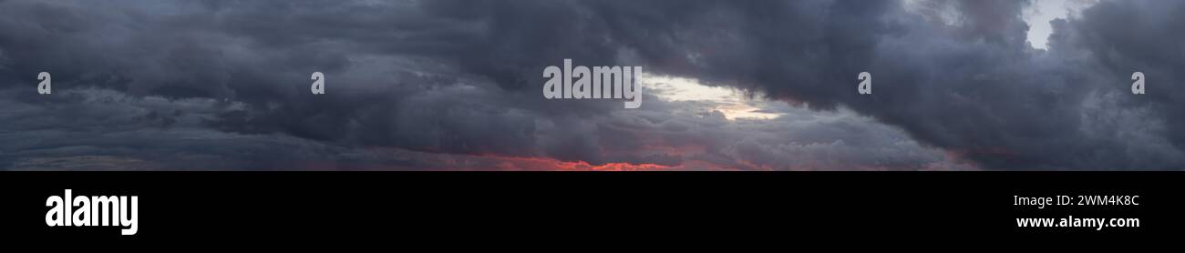 Ultrawide panorama dramatic sunset with vibrant clouds lit by a sun ...