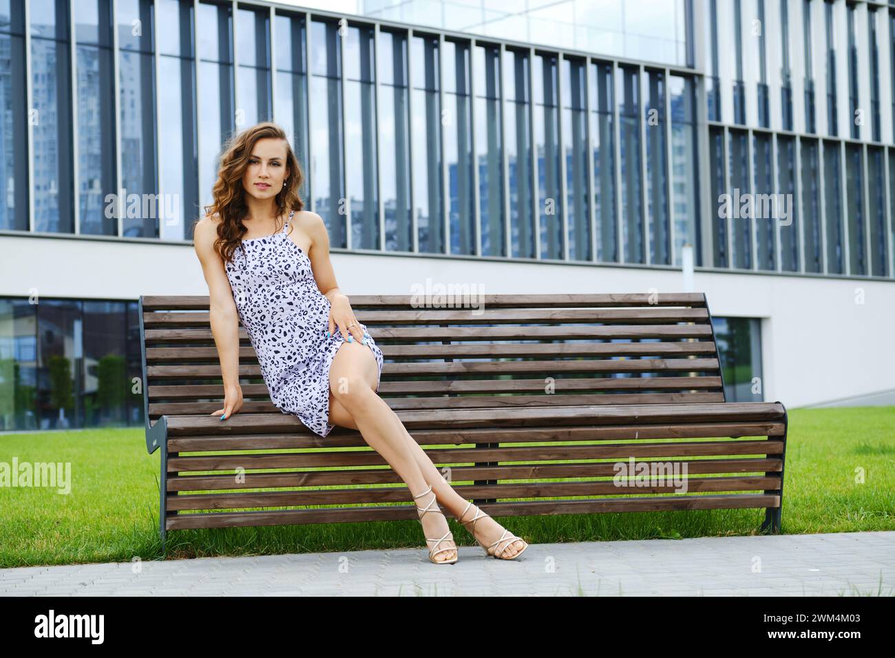 Beautiful woman in sundress with long legs sitting on bench Stock Photo ...