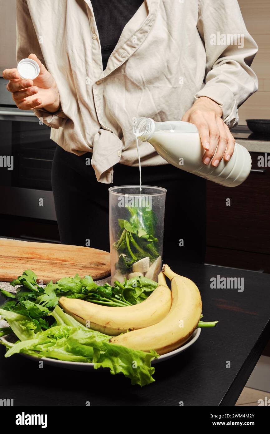 Unrecognizable Woman Pouring Milk Into Blender With Banana And Spinach