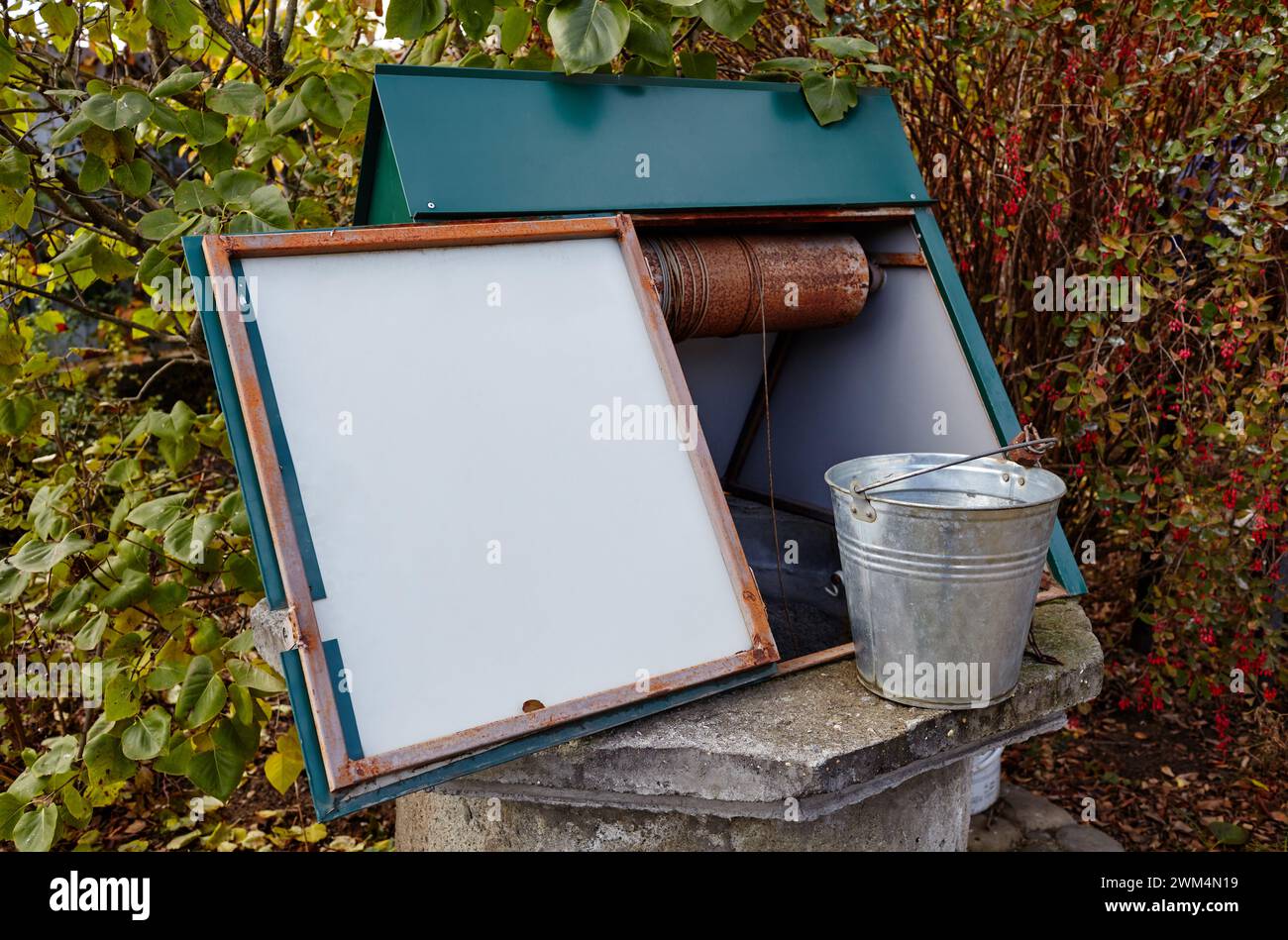 Metal bucket at draw-well in European village. Retro stone water well ...