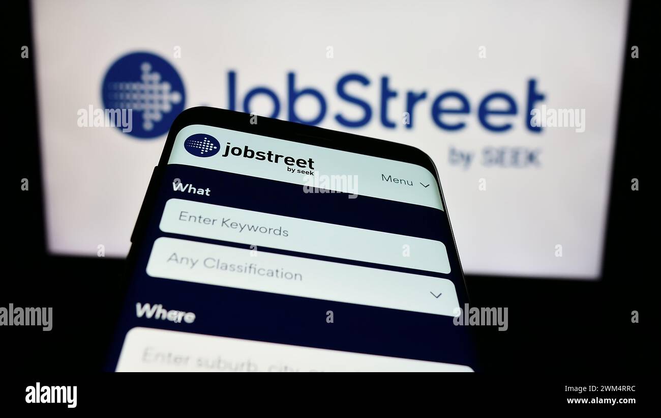 Mobile phone with website of employment platform company Jobstreet in front of business logo ...