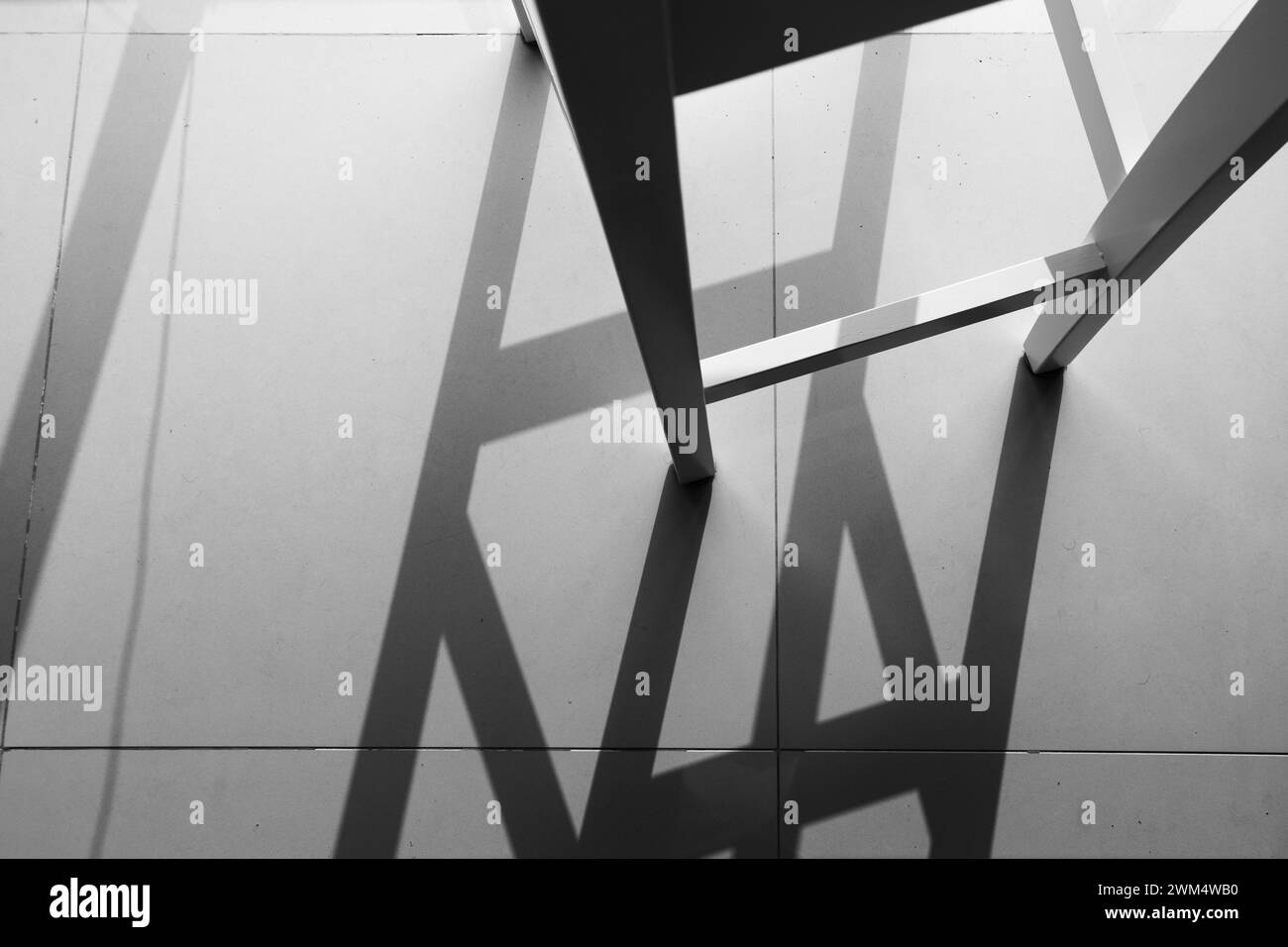 Sunlight shines through a window casting a strong shadow of a chair on ...