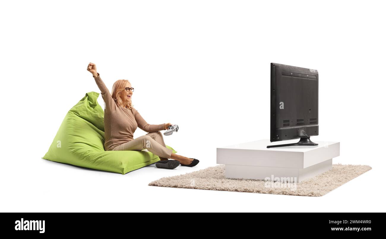 Middle aged woman playing video games in front of tv isolated on white ...