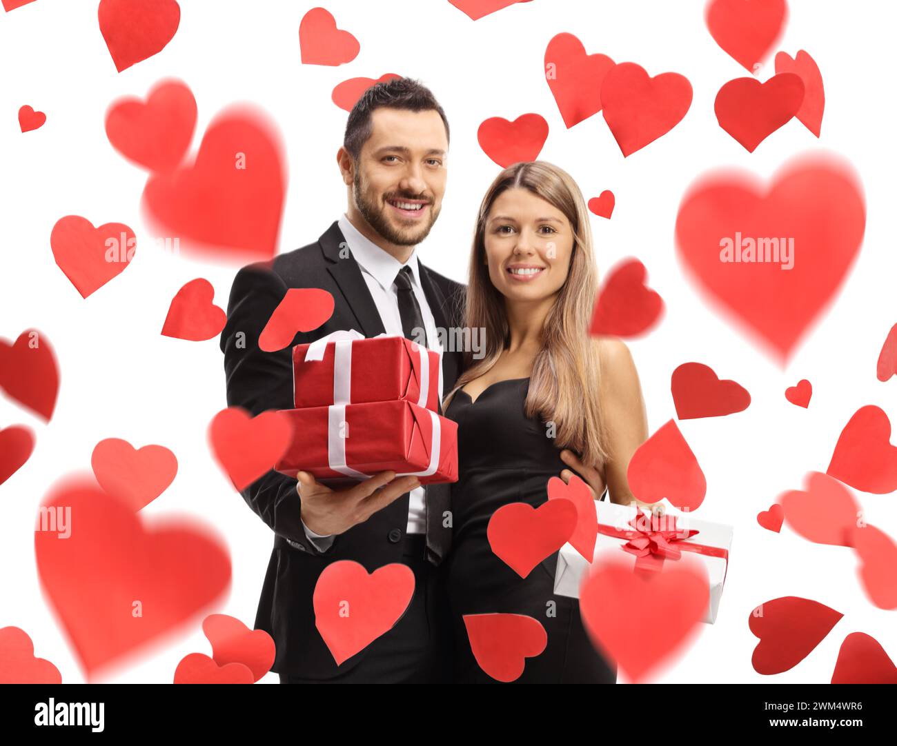 Young couple holding presents under a rain of hearts isolated on white ...