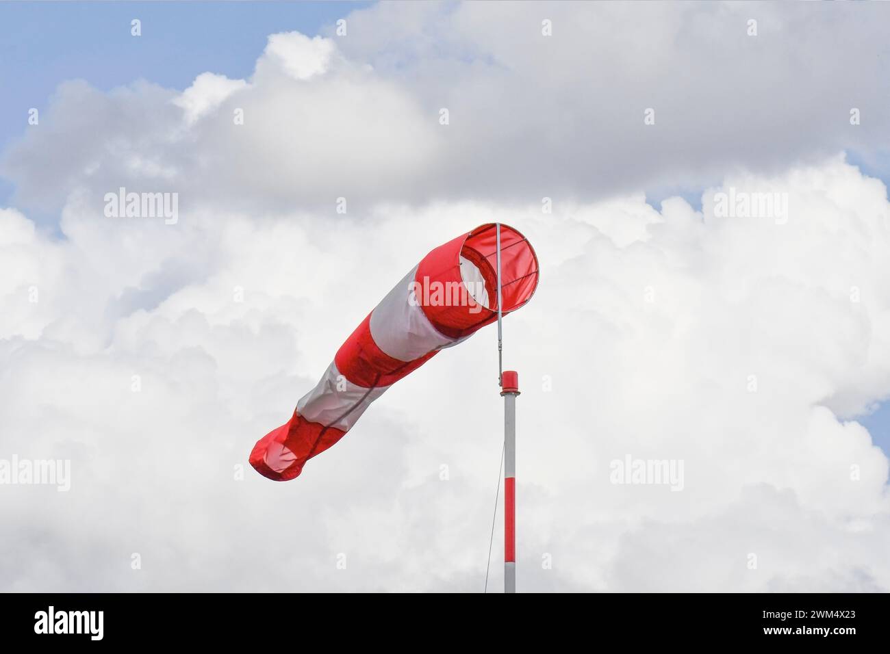 Red and white windsock, on clouds sky, windy weather forecast concept ...