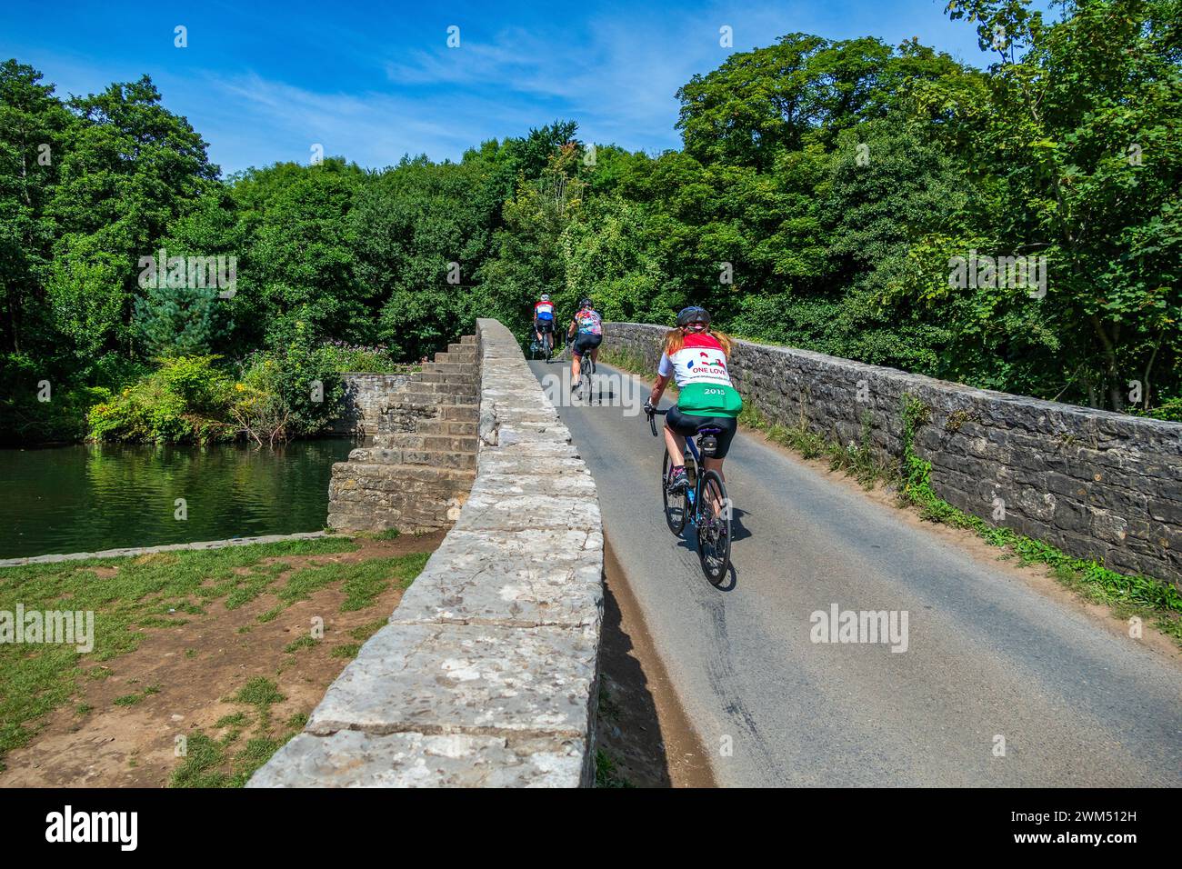 group of cyclists crossing medieval bridge gower peninsula south wales ...