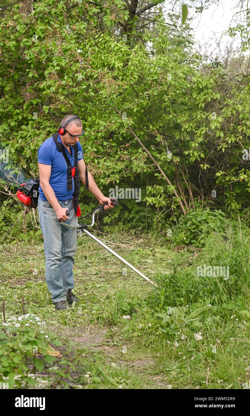 The gardener mows weeds. Process of lawn trimming with hand mower Stock ...