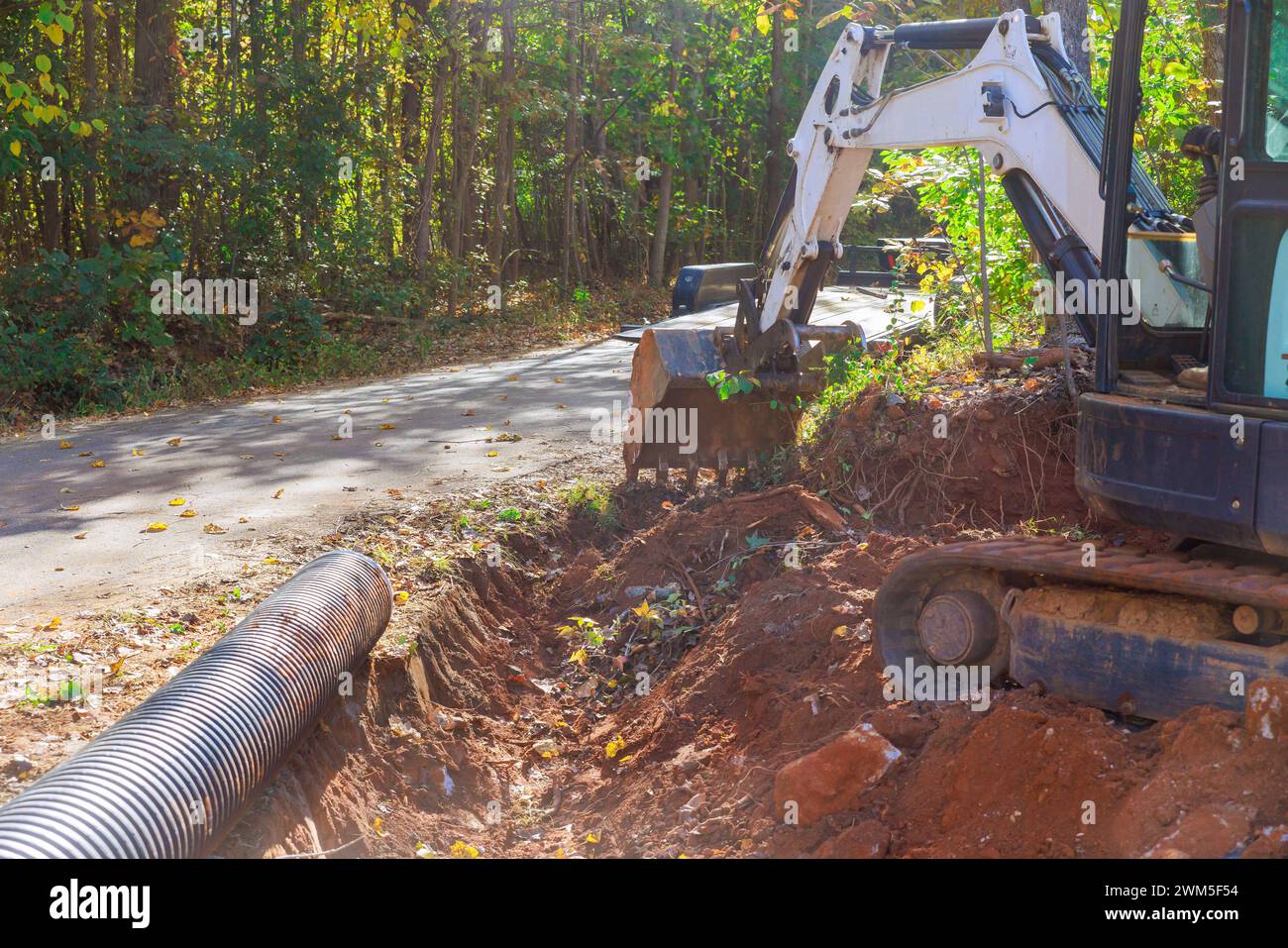 Excavator dig trenches for laying piping that will carry rainwater to ...