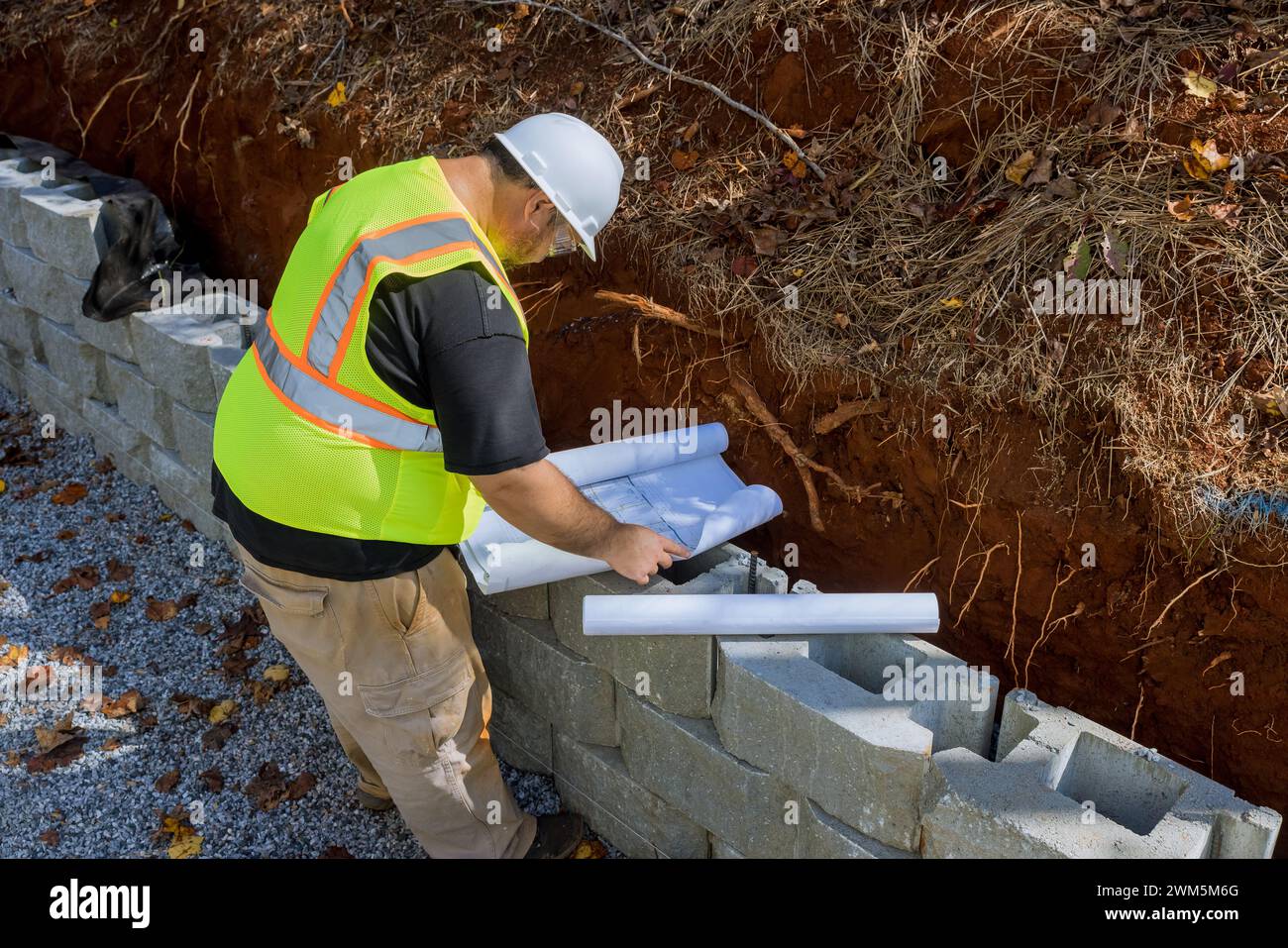 When mounting retaining walls with cement blocks, construction workers ...