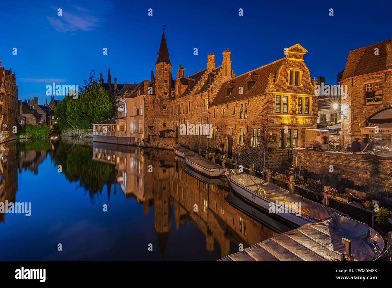 Center of the Hanseatic city of Bruges on the Rosary Quay canal. Illuminated historic buildings ...