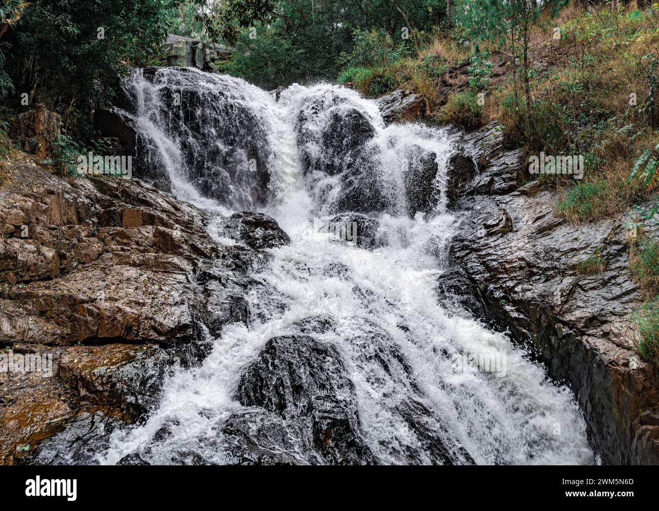 small waterfall with water flowing over brown stones. natural landscape ...
