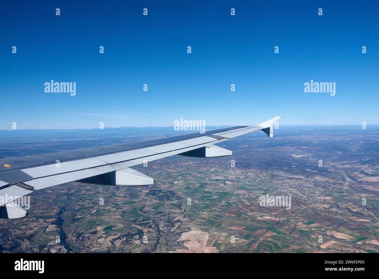 An aerial view from an airplane showing the wing and landscape below ...