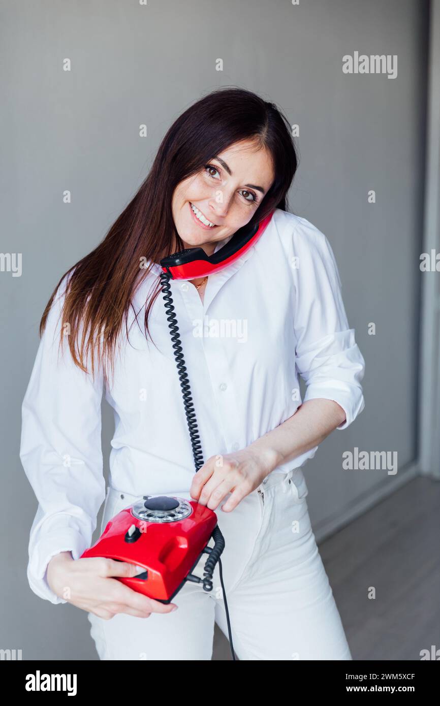 Brunette woman talking on old wired phone Stock Photo - Alamy