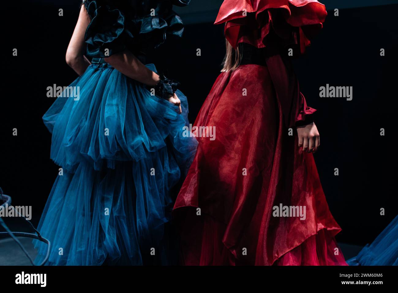 Long fluffy evening red and blue dresses on a female figures on a black ...