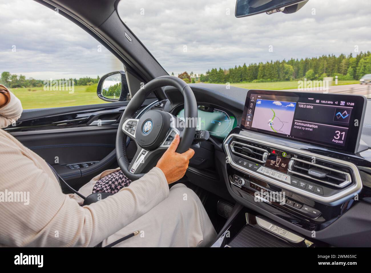 Close-up view of a woman behind the wheel of the BMW iX3 M electric car ...