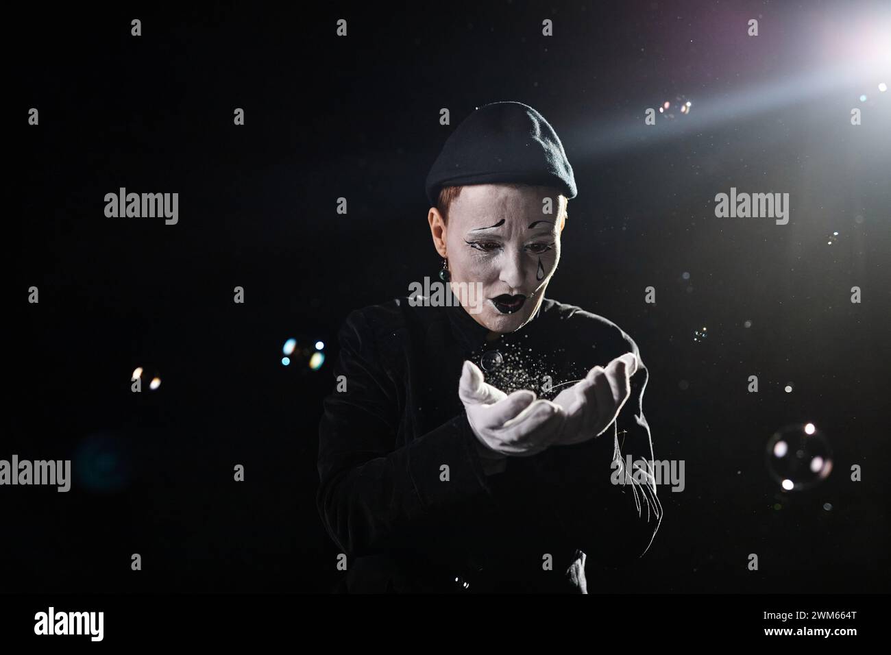 Minimal portrait of mime artist playing with soap bubbles and catching ...