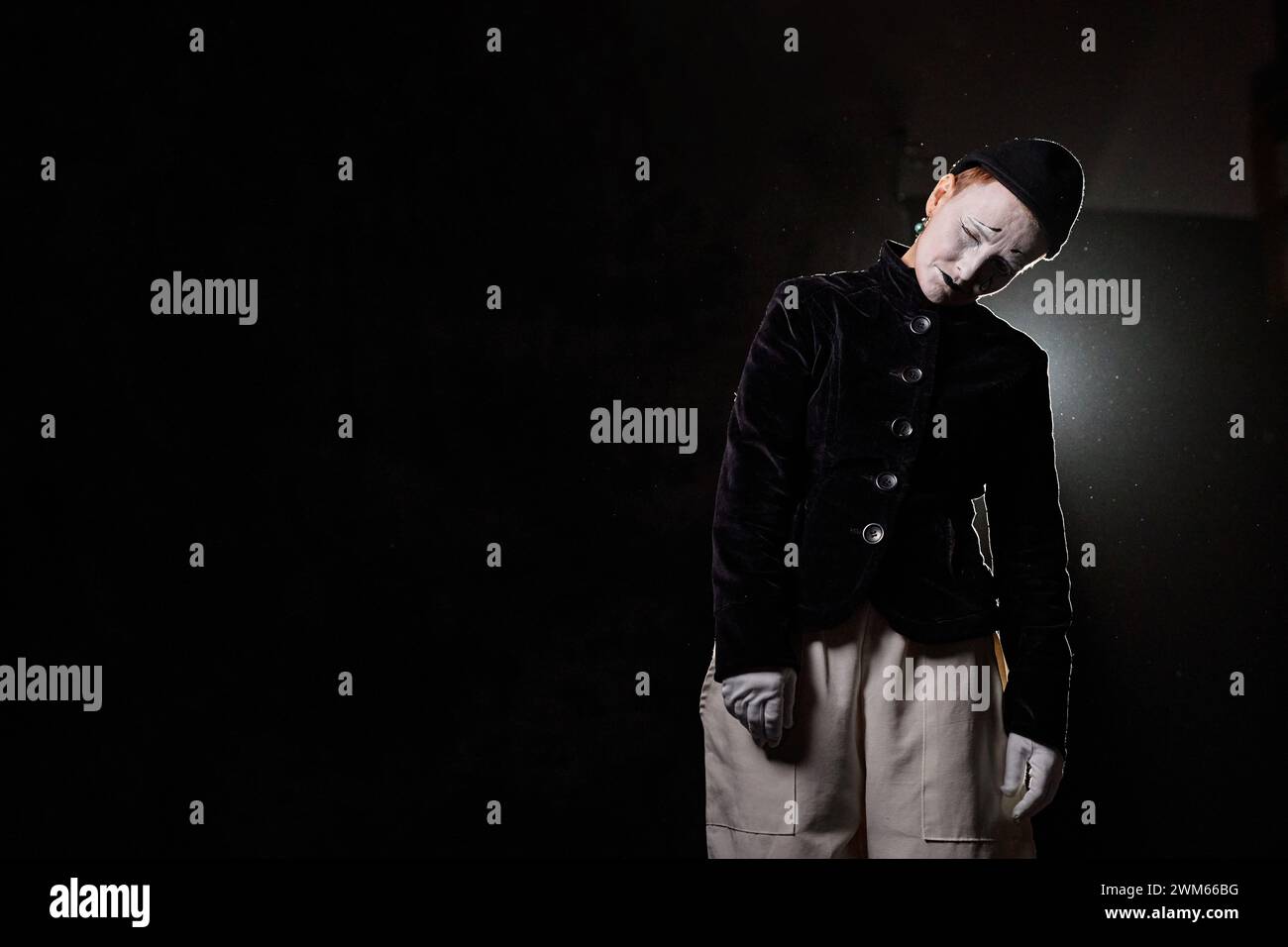 Minimal portrait of sad mime performer on black with contouring light ...