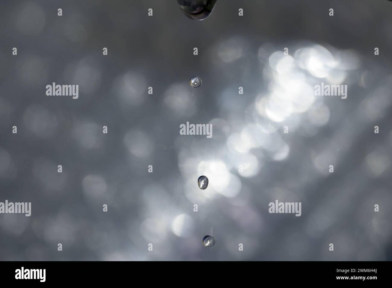 Small water drops coming out of faucet dripping with bright background ...