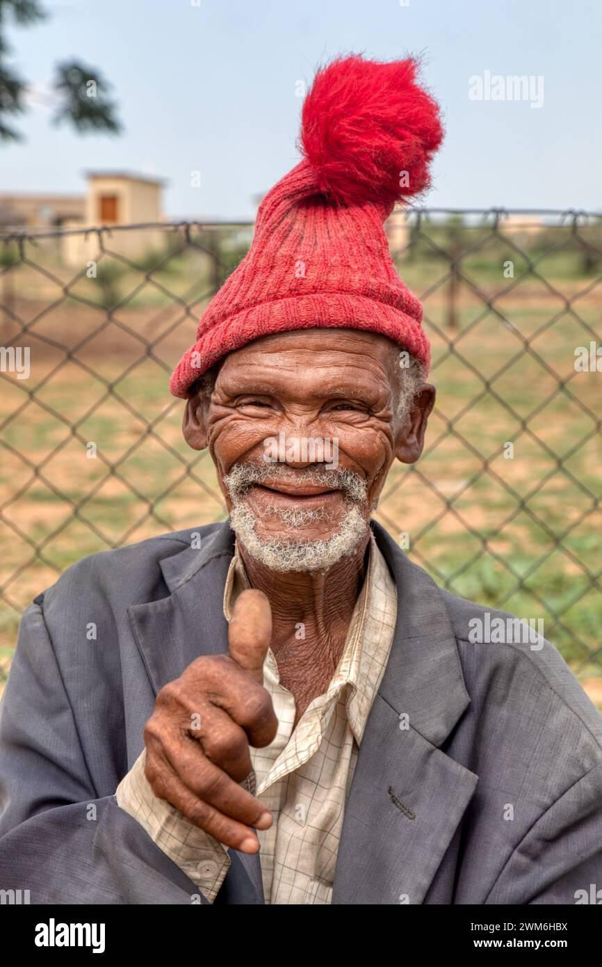 village old african man standing in the yard, in the background blue ...