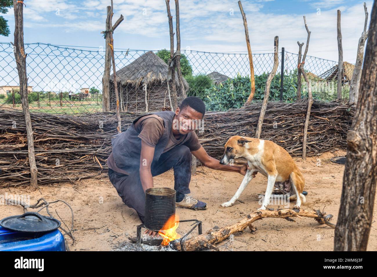 village african man and his dog in the outdoors kitchen cooking, in ...