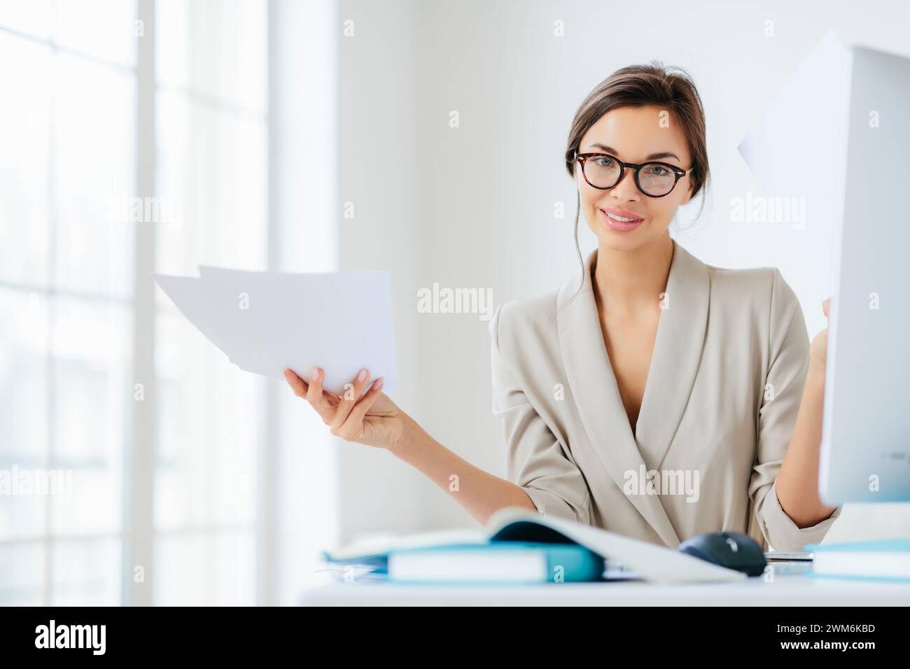 Smiling businesswoman holding documents with a sense of accomplishment ...