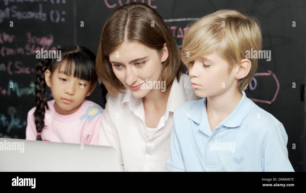Young smart teacher using laptop to teach diverse student programing system. Caucasian learner ...